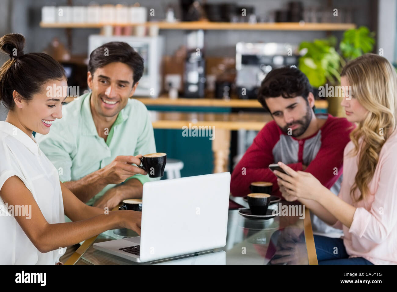 Group of friends using mobile phone and laptop Stock Photo - Alamy
