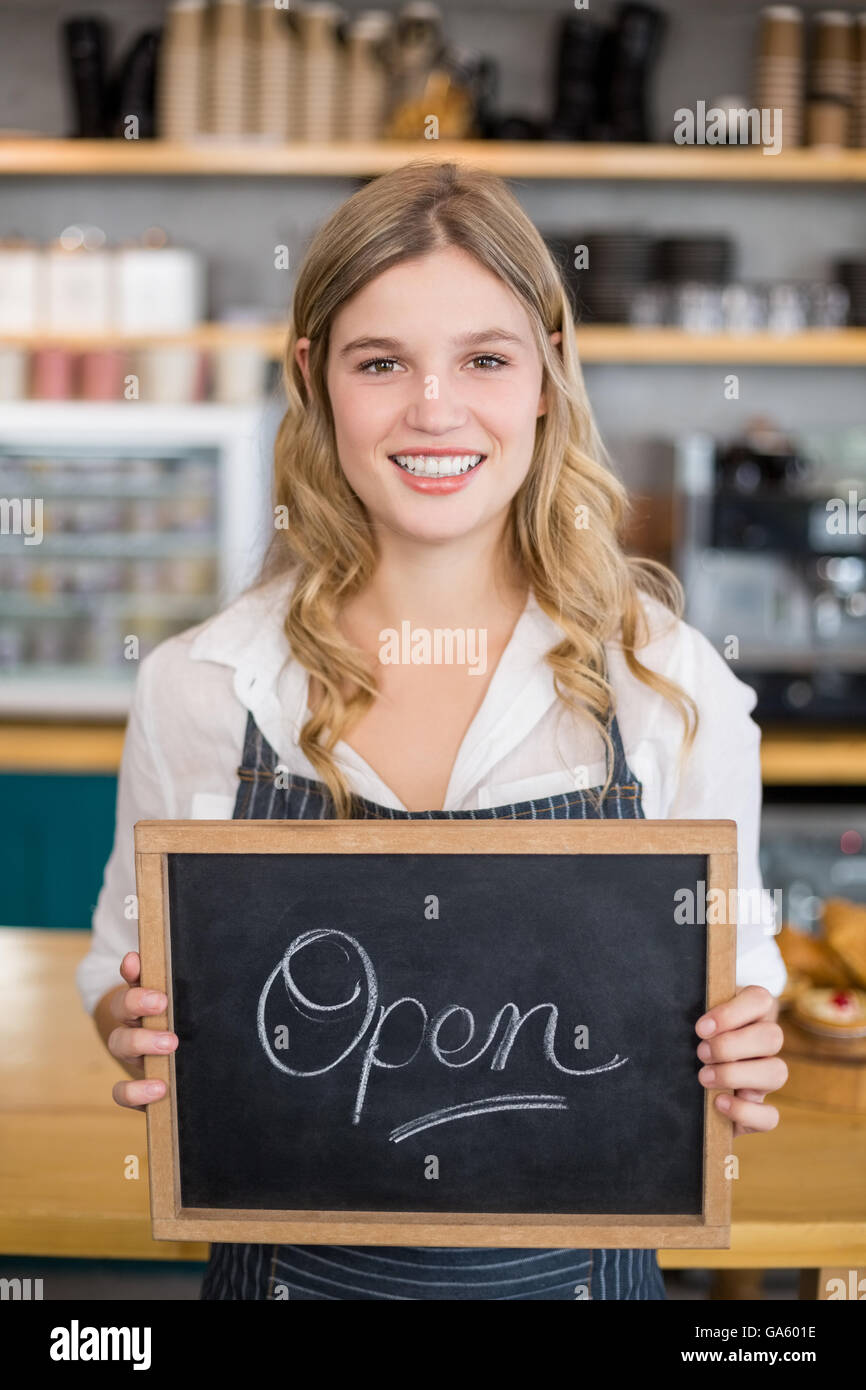 Smiling waitress showing chalkboard with open sign at cafe Stock Photo ...