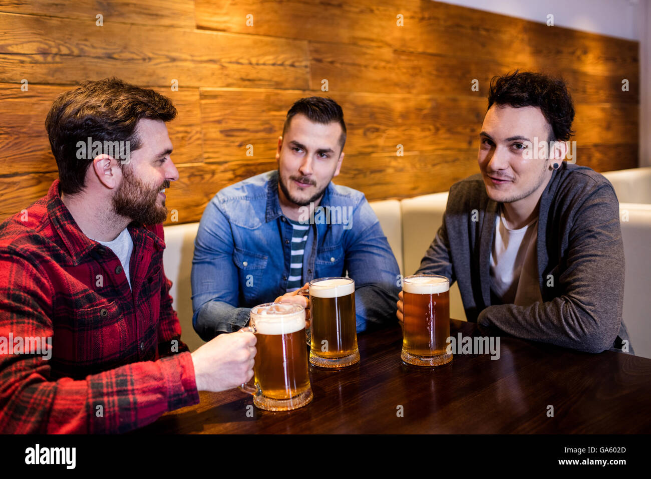 Young friends enjoying beer at restaurant Stock Photo - Alamy