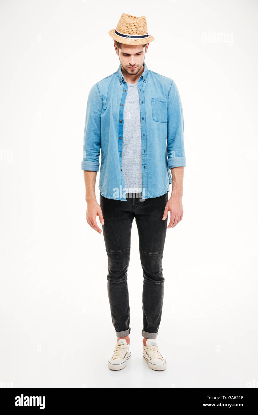 Sad upset young man in hat standing and looking down over white ...