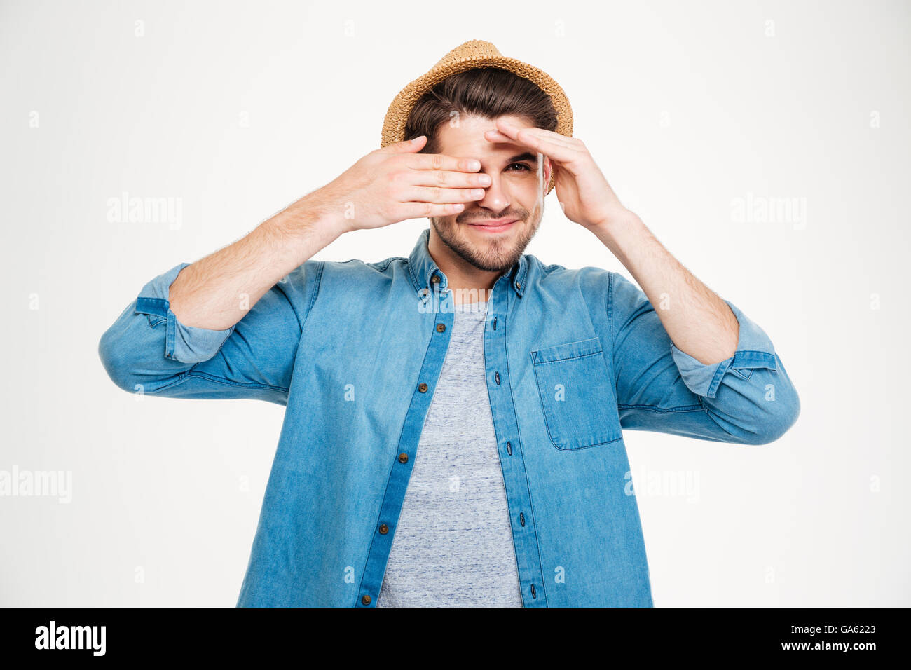 Happy cute young man covered one eye with hand and smiling over white ...