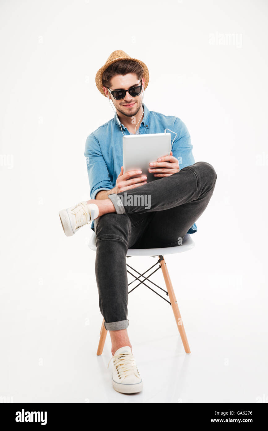 Handsome attractive happy joyful young man using tablet and sitting on ...