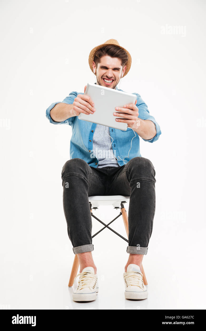 Portrait of a funny casual man playing using tablet computer isolated ...