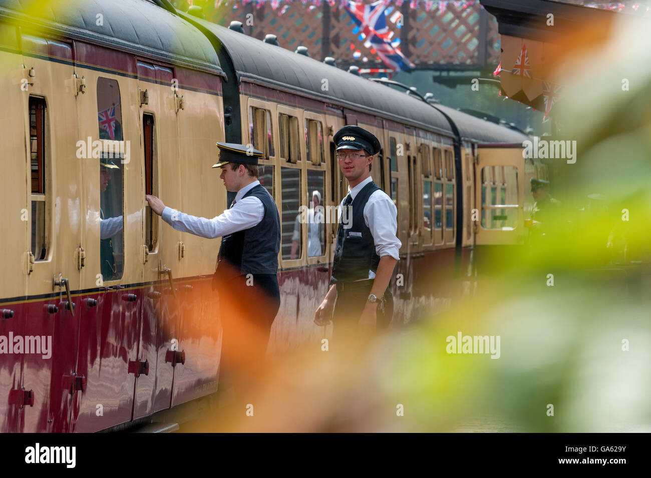 two train guards walking along the platform next to a steam train Stock ...