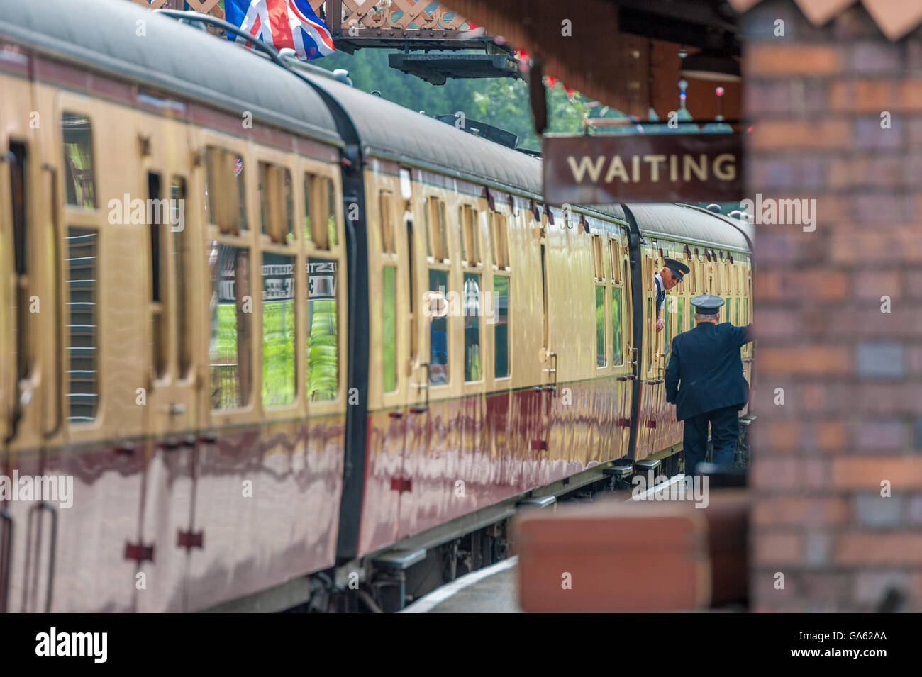 A steam train on the platform with a guard looking out the window ...