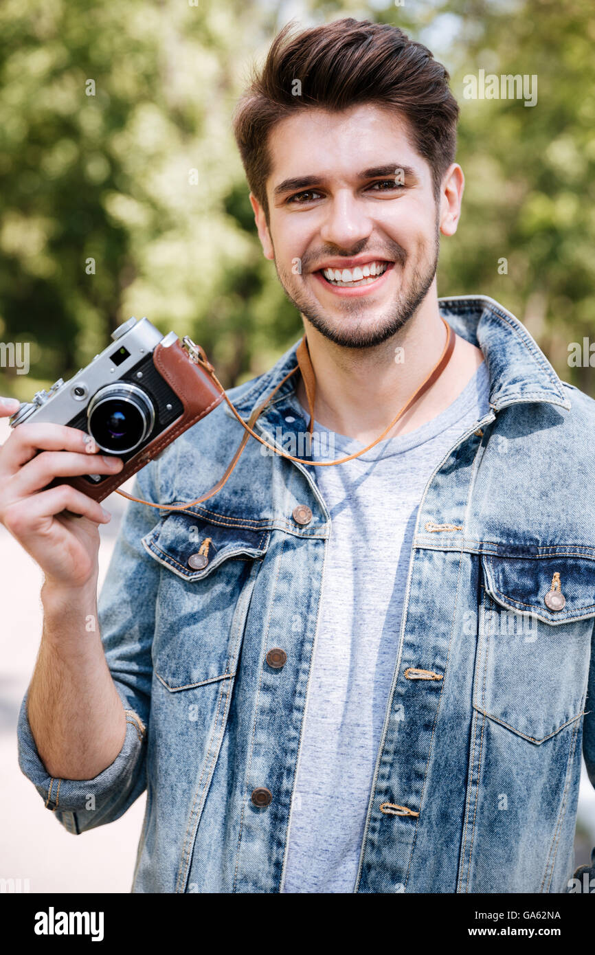 Close-up portrait of a handsome hipster guy holding camera outdoors in ...