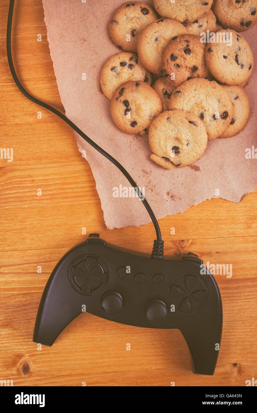 Gamepad and homemade chocolate chip cookies on rustic wooden table, top ...