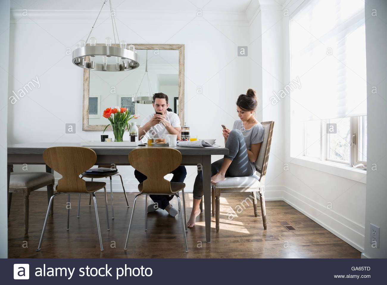 Couple texting with cell phones at breakfast dining table Stock Photo ...