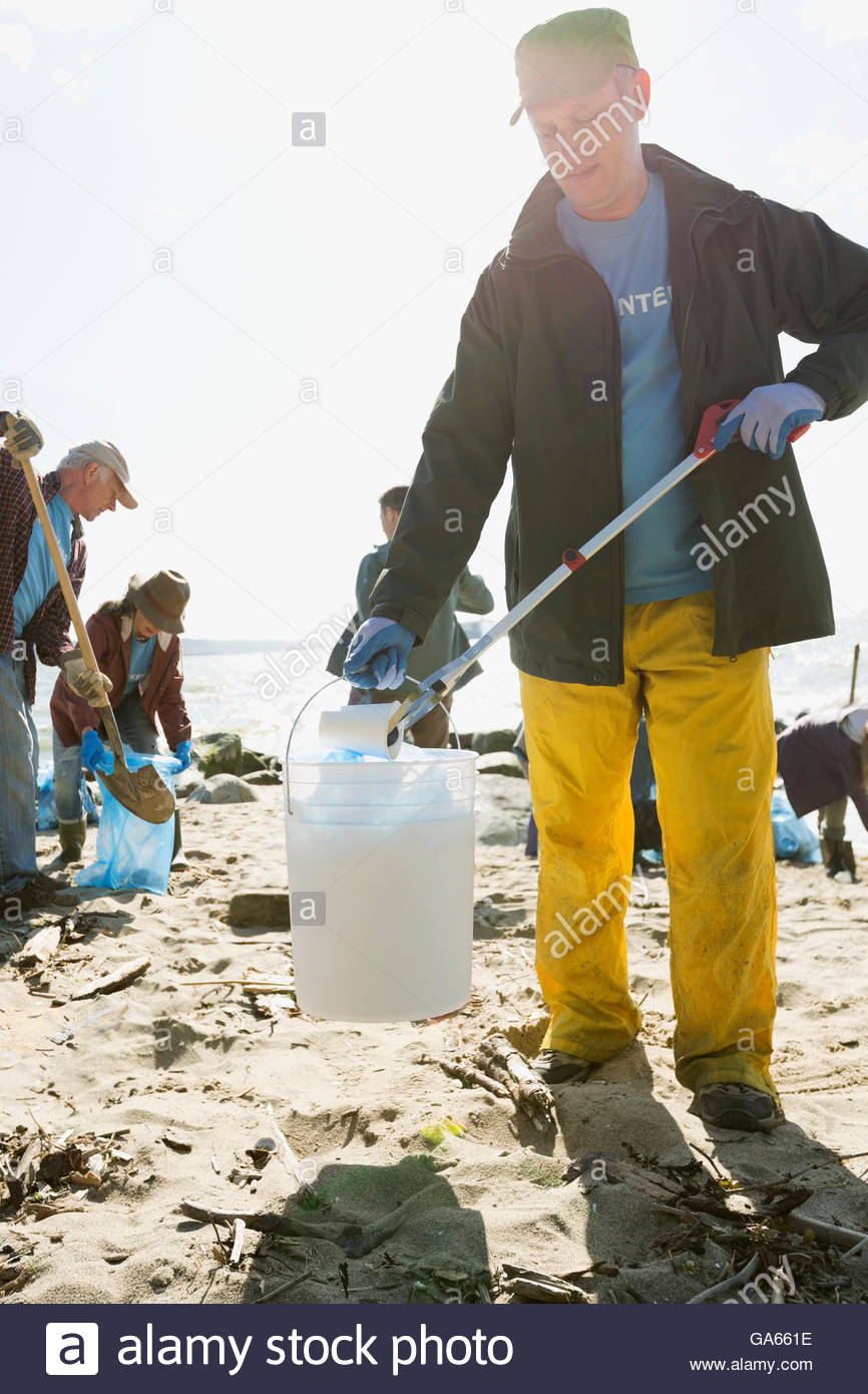 Beach cleanup volunteer using claw to pick up litter on beach Stock ...