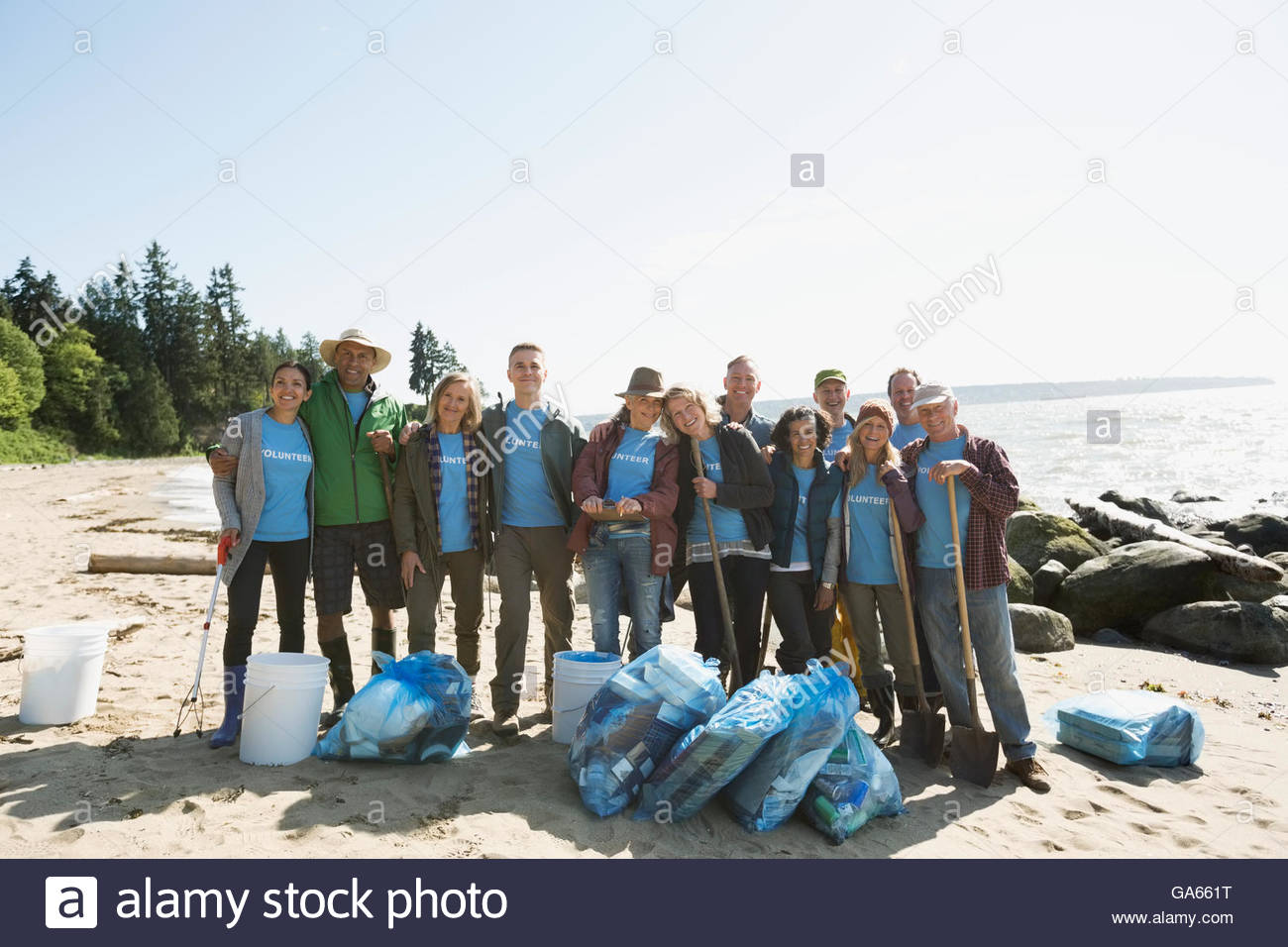 Portrait smiling beach cleanup volunteers on sunny beach Stock Photo ...