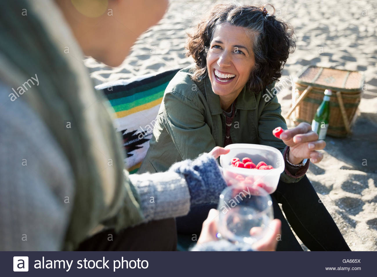 Smiling women eating raspberries at beach picnic Stock Photo - Alamy