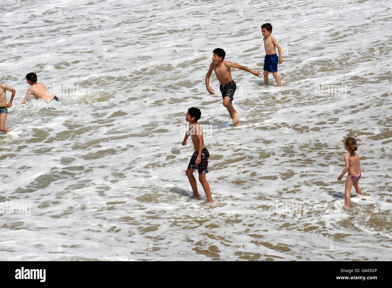 Children playing on beach waiting for a wave Stock Photo - Alamy