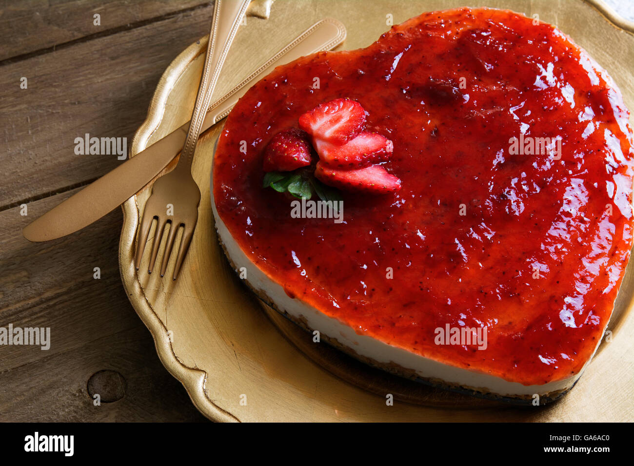 Heart shaped cheesecake with raspberry jelly on a gold plate decorated ...