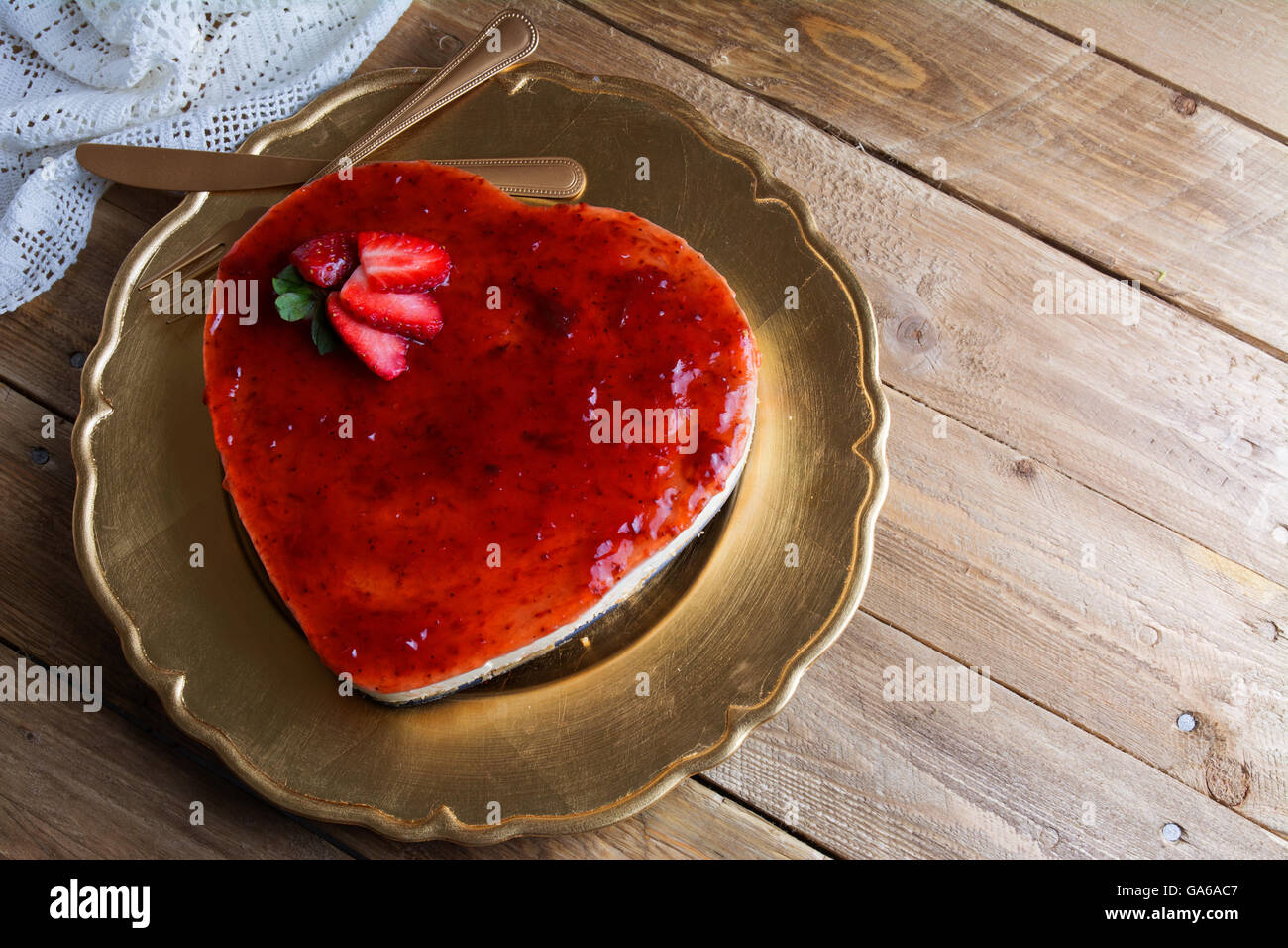 Heart shaped cheesecake with raspberry jelly on a gold plate decorated ...