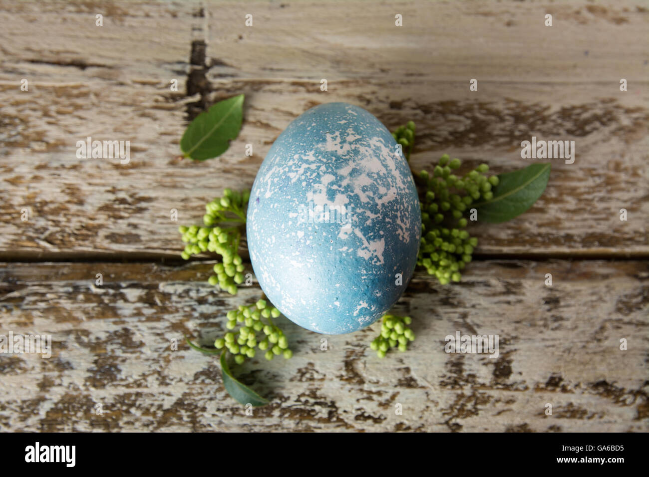 Blue Easter egg, decorated with flowers, on wooden board. closed flat ...
