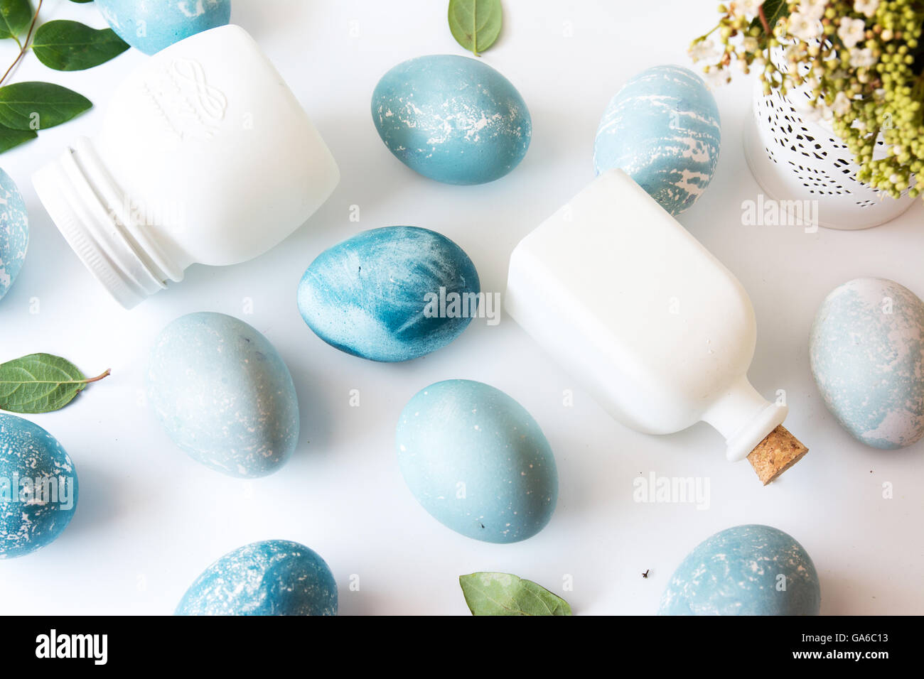 Blue Easter eggs, white bottles and flowers on white surface Stock ...
