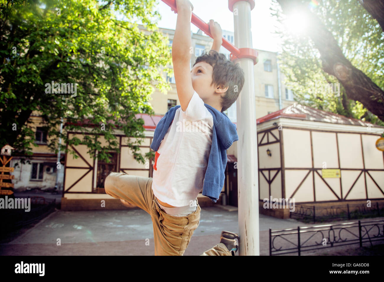 little cute blond boy hanging on playground outside, alone training ...
