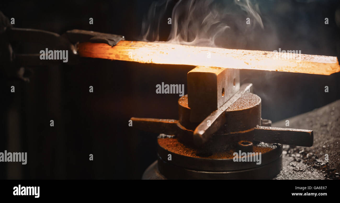 Rod hot iron on the anvil ready to be beaten Stock Photo - Alamy