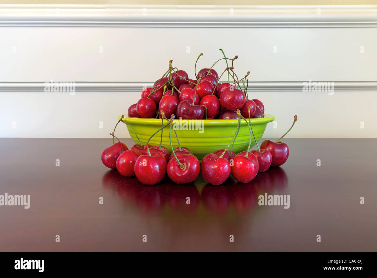 Pile of Bing Cherries in green bowl and on wood table with reflection ...