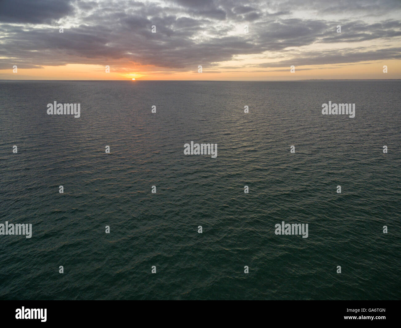 Sunset over calm waters of the ocean Stock Photo - Alamy