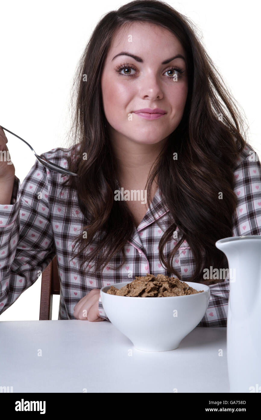studio shot of a pretty model wearing her pyjamas, sitting at a table ...