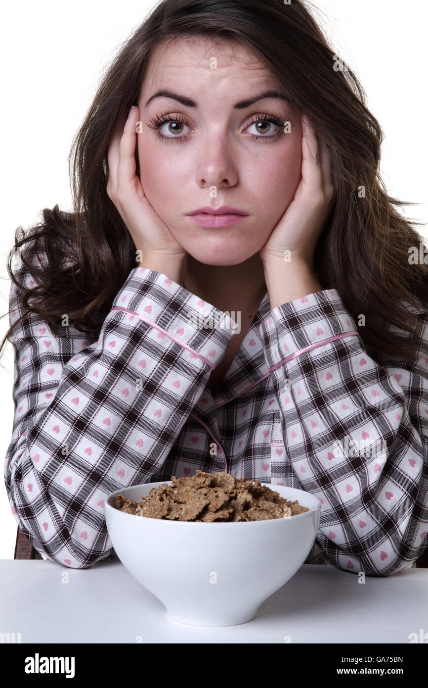 Very tired model, sitting at the breakfast table with a bowl of cereal ...