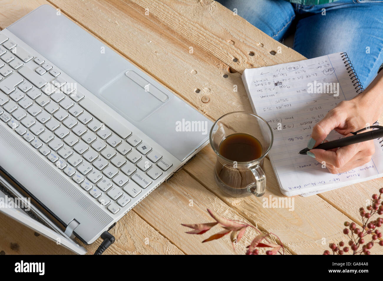 Woman at the computer, writing in a notepad, wearing plaid shirt and ...