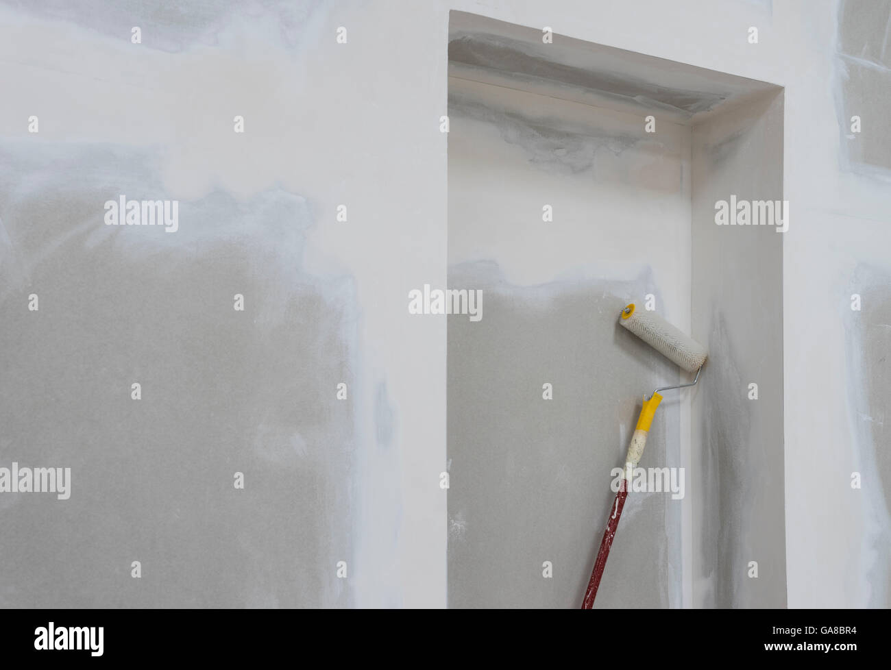 Unfinished wall and paint roller Stock Photo - Alamy