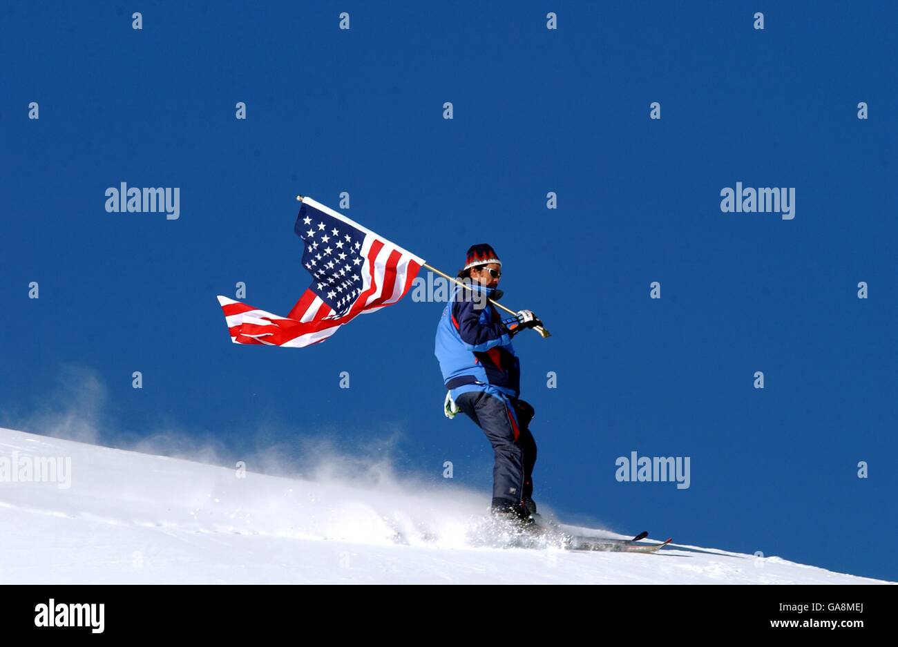 A skier holds aloft the American flag at the Snowbasin ski area venue ...