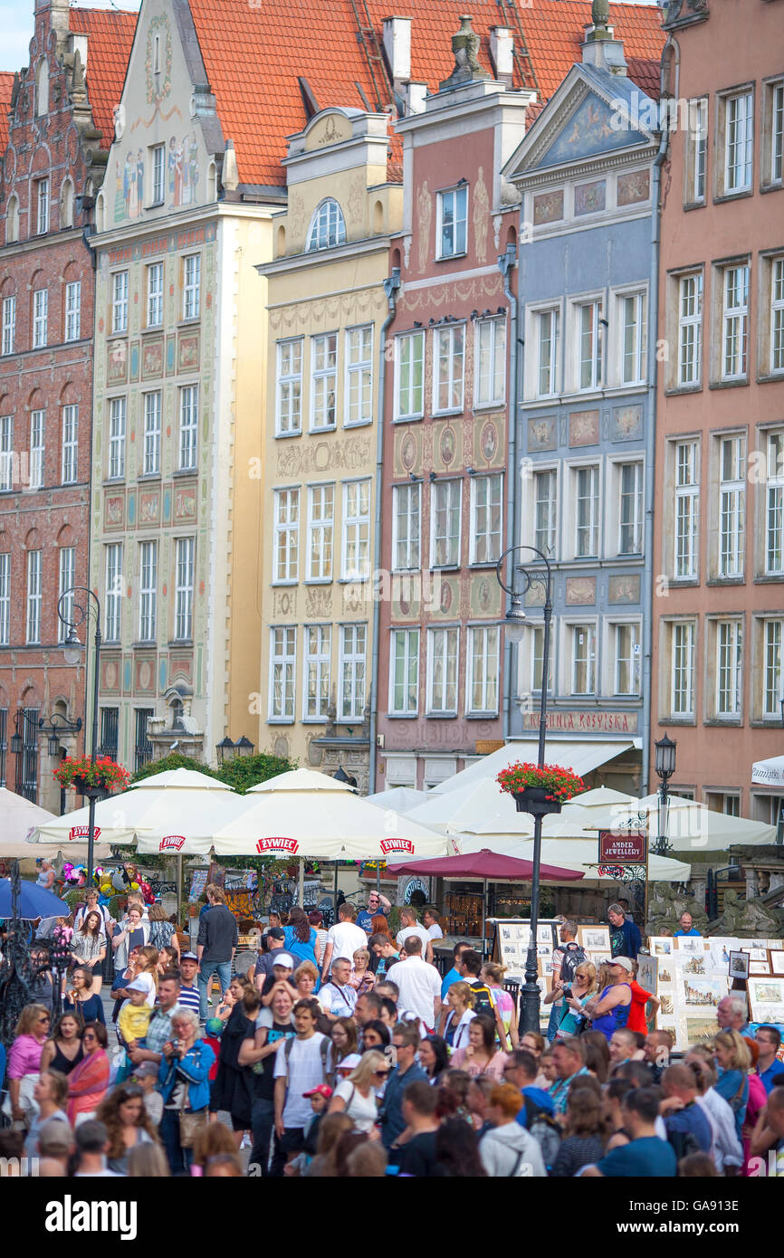 Summer crowds walk past terraced historical buildings and architecture ...