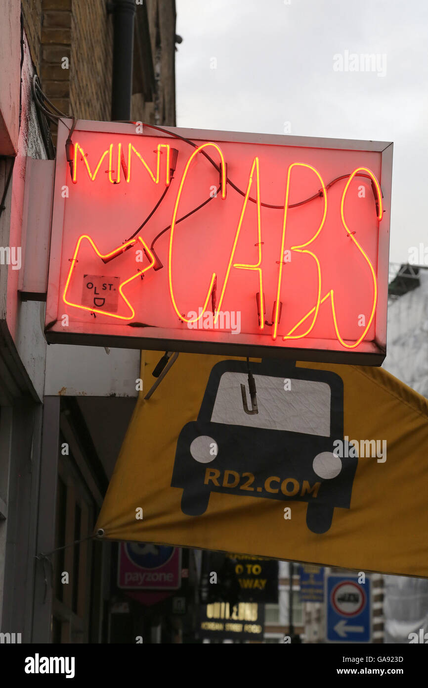 A neon sign advertises the office of a minicab office in London ...