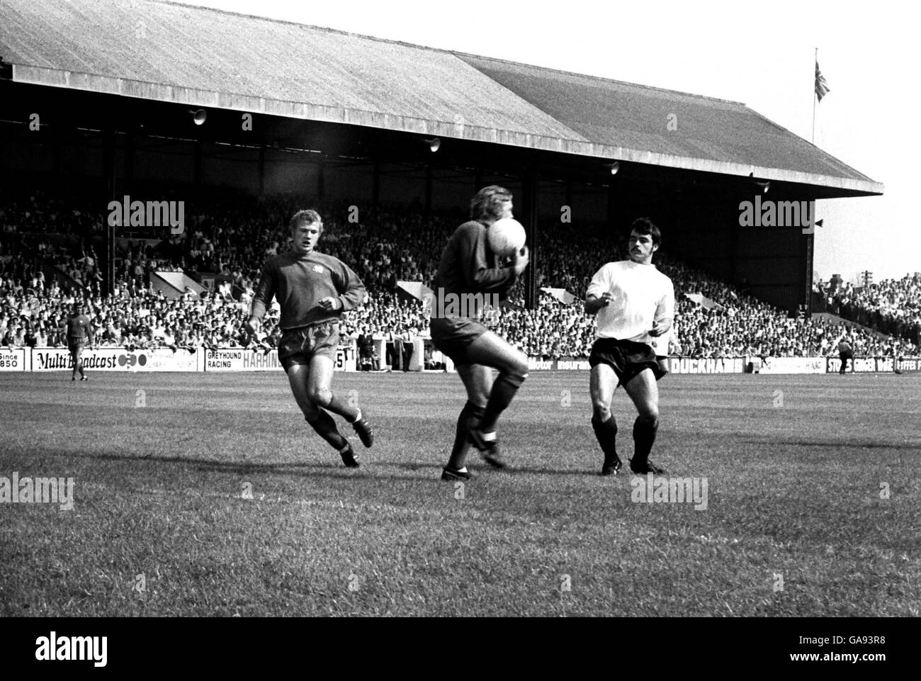 (L-R) Orient's Dennis Rofe looks on as goalkeeper Ray Goddard saves ...