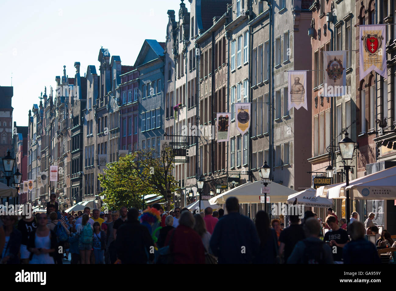 Summer crowds walk past terraced historical buildings and architecture ...
