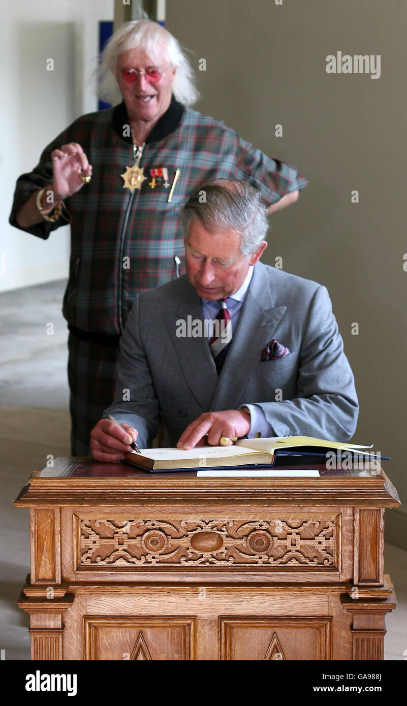 Sir Jimmy Savile mimics Prince Charles as he signs a book during his ...