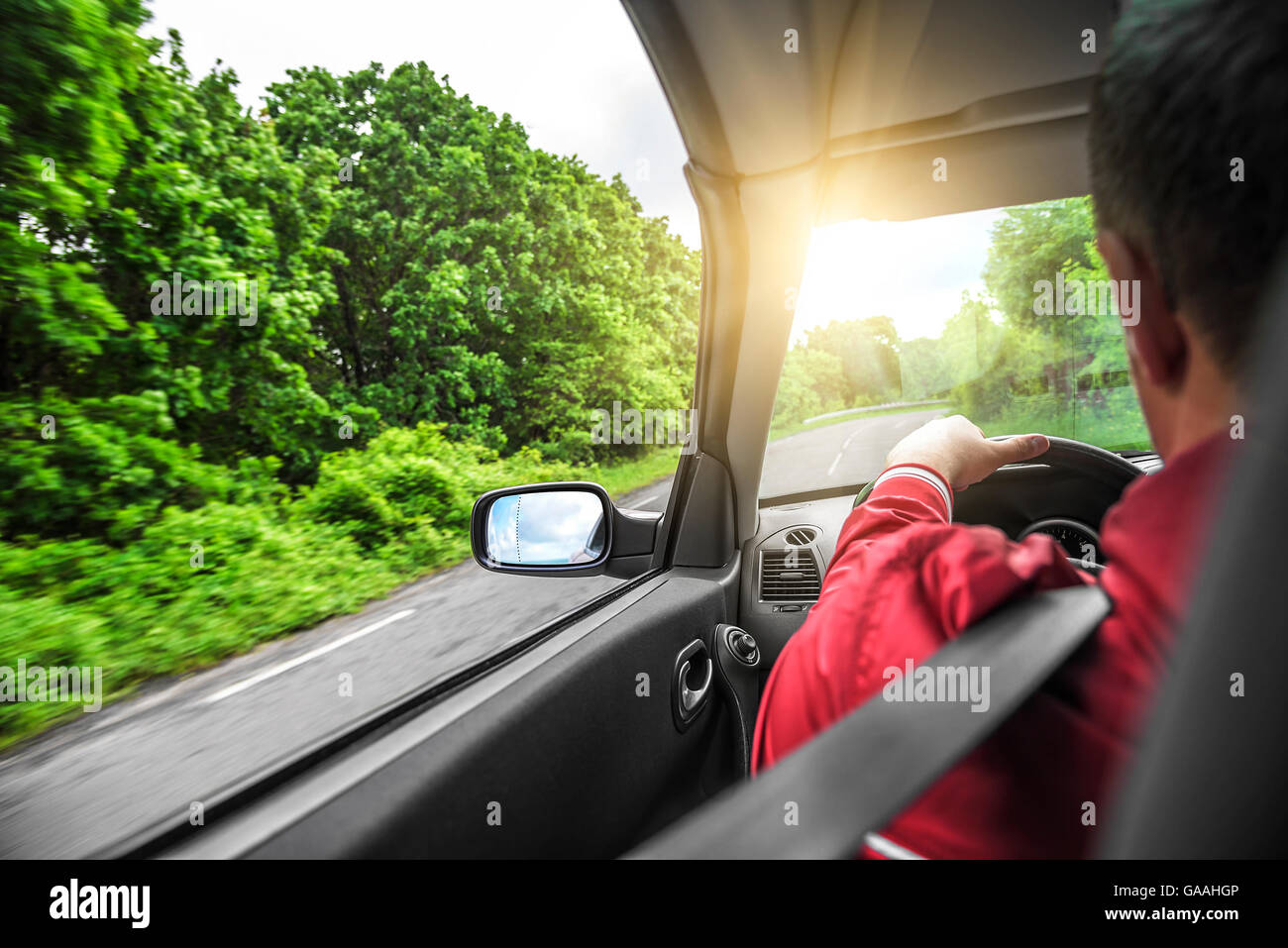 Male driver drives a convertible car on the country road. The view from ...