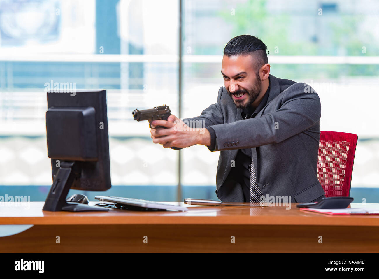 Angry aggressive businessman with gun in the office Stock Photo - Alamy