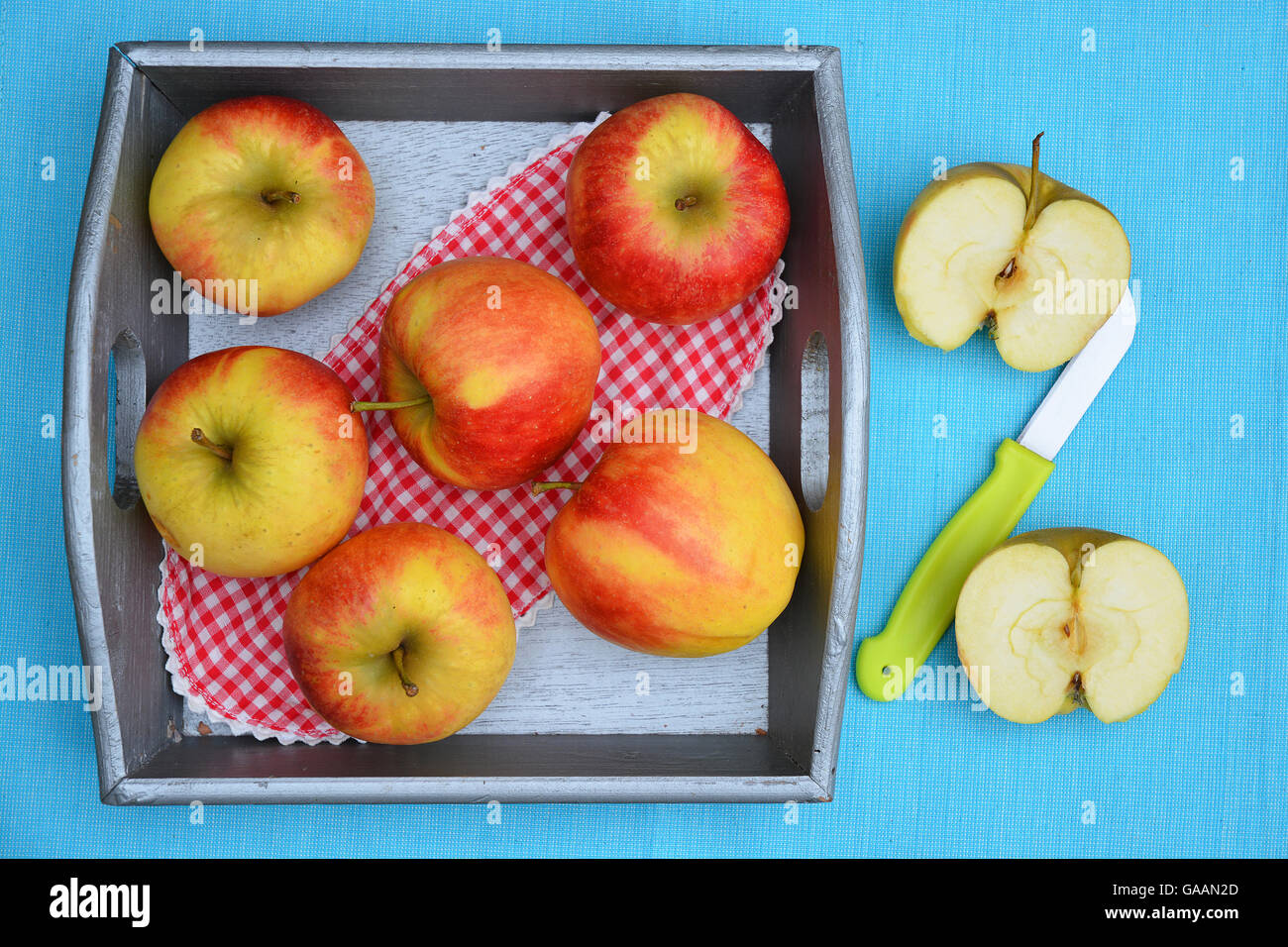 Fresh cut shiny apples in a wooden basket with a knife and red and ...