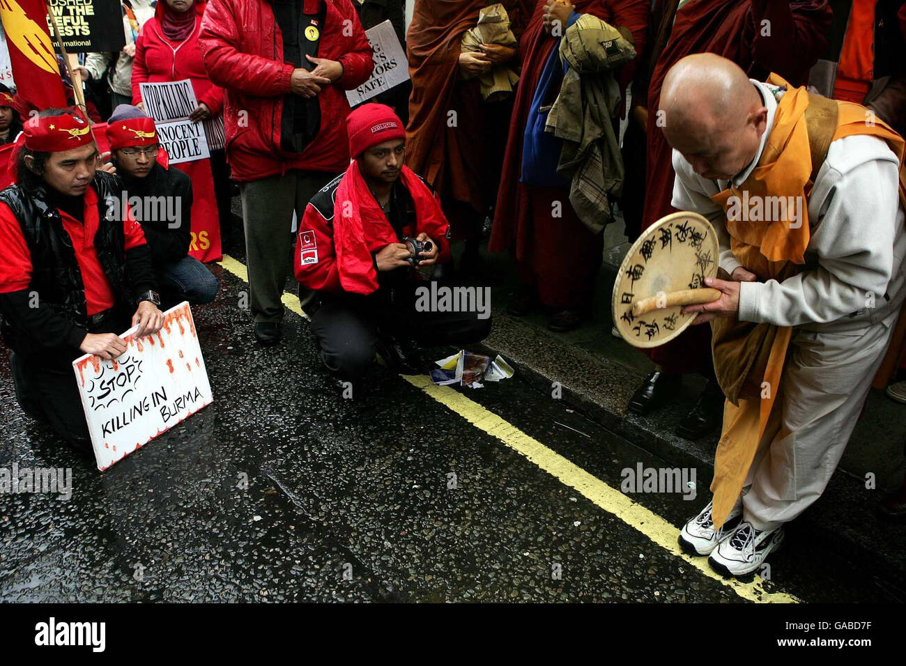A Buddhist monk prays in heavy rain outside the Union of Myanmar ...