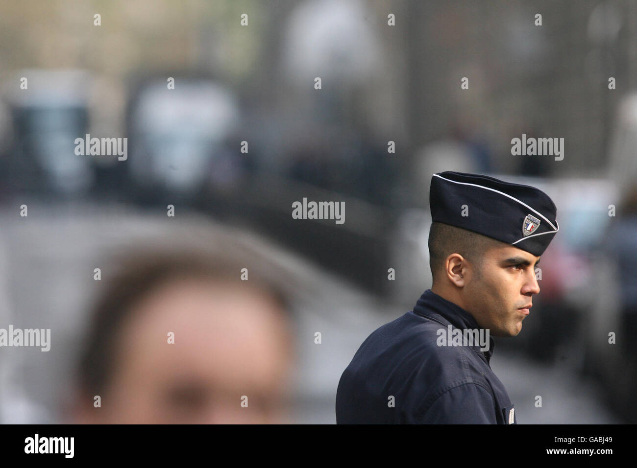A French police officer stands on the corner of the street at the back ...