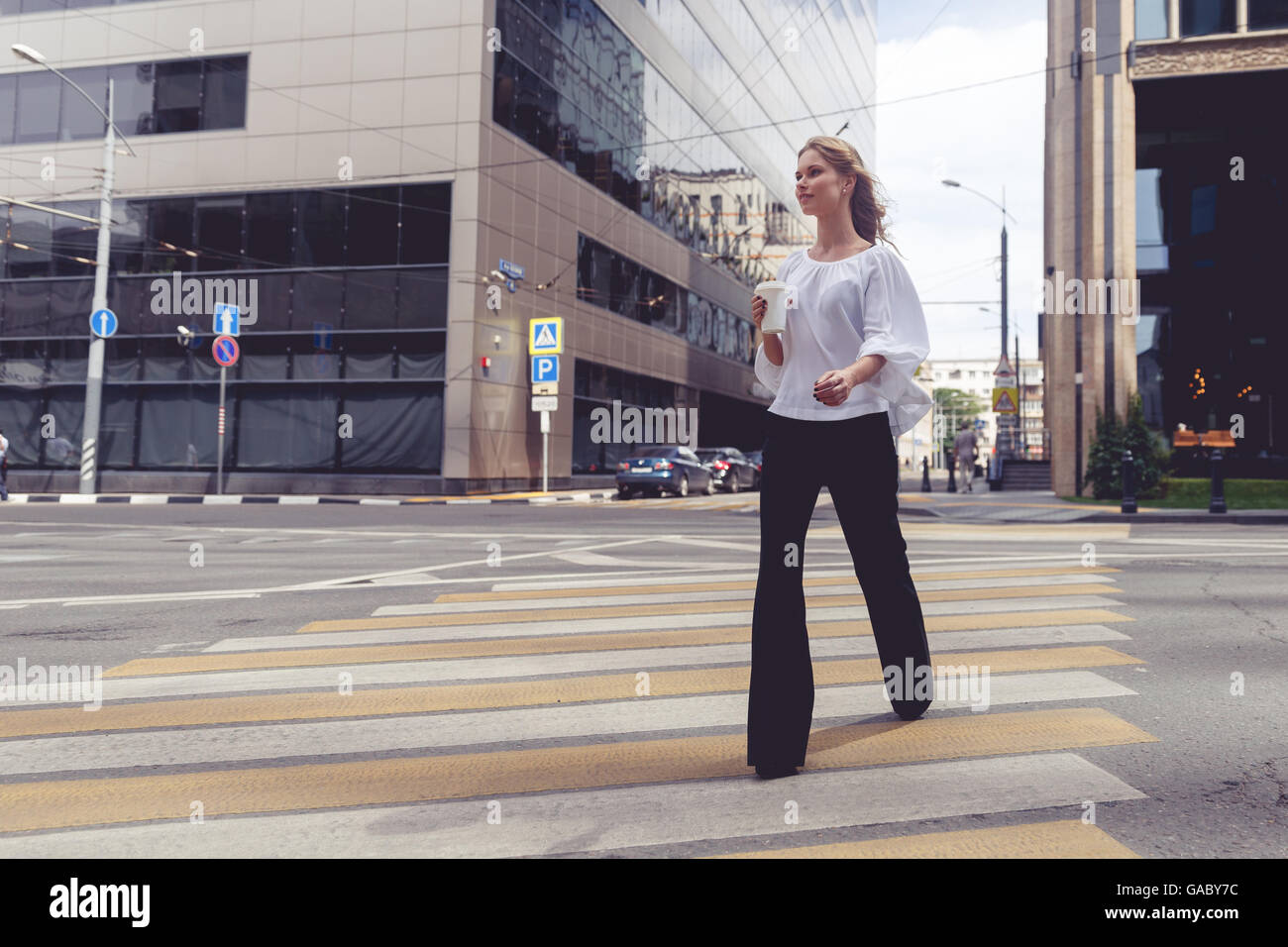 Beautiful woman crossing on crosswalk and holding coffe Stock Photo - Alamy