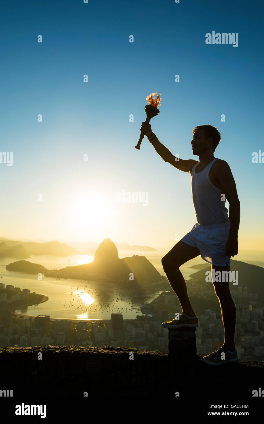 Torchbearer athlete holding sport torch in silhouette against the ...