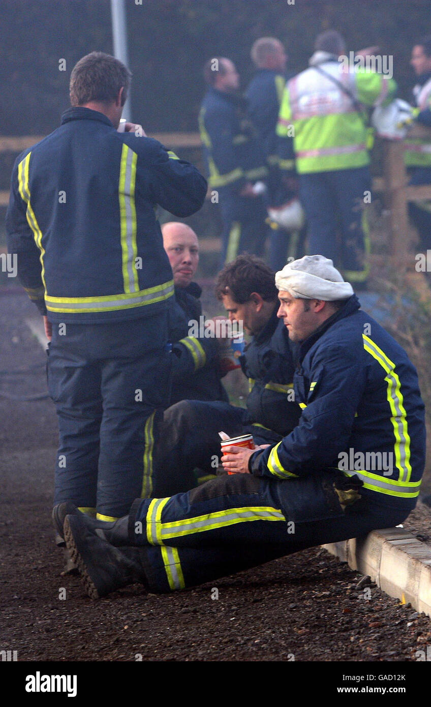Firefighters take a break from battling a fire that is blazing at a ...