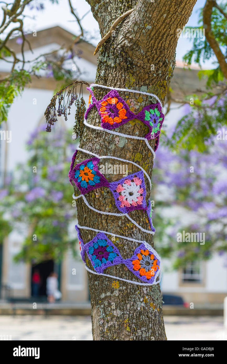 Yarn bombing. A tree dressed with knitted colorful wool. European park ...