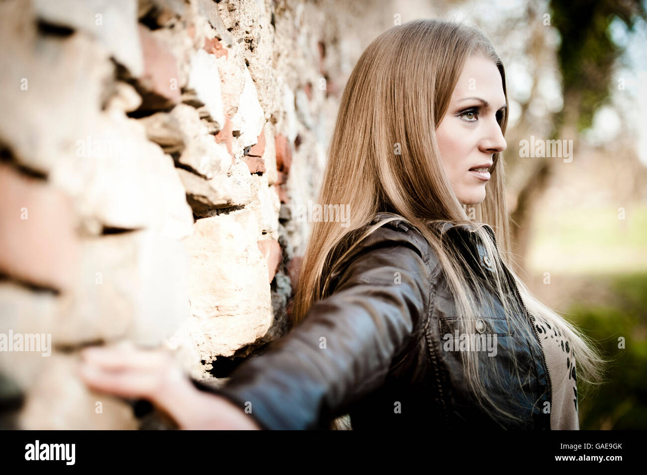 Young woman leaning against a wall Stock Photo - Alamy