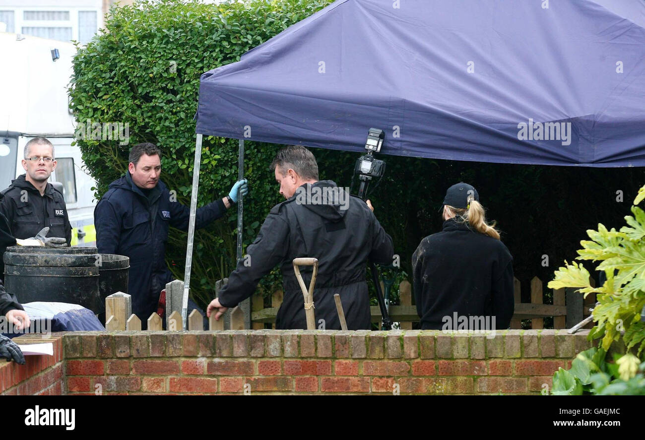 Police search officers at work in the front garden of the former home ...