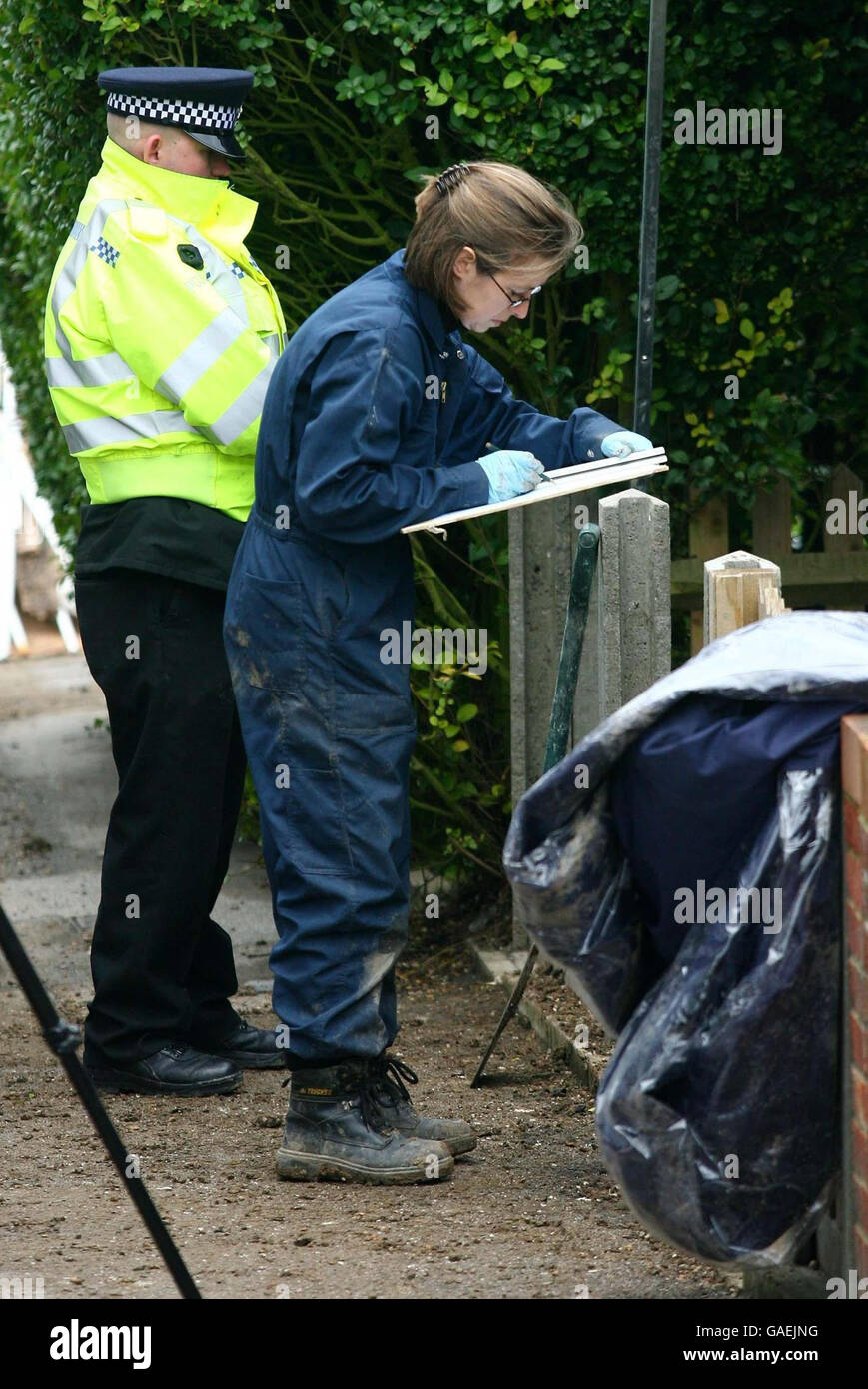 Police search officers at work in the front garden of the former home ...