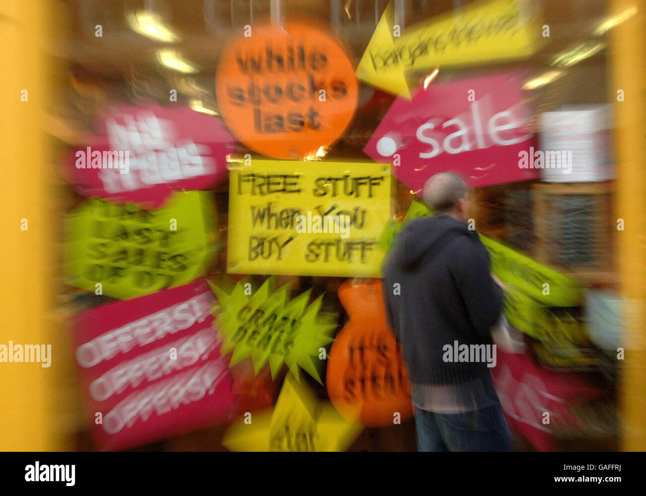 A shopper looks through a shop window while looking for bargains in the ...