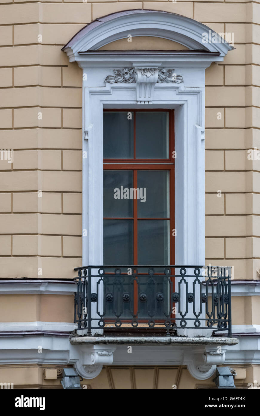 A window with an arch and balcony on the facade of the beige building ...
