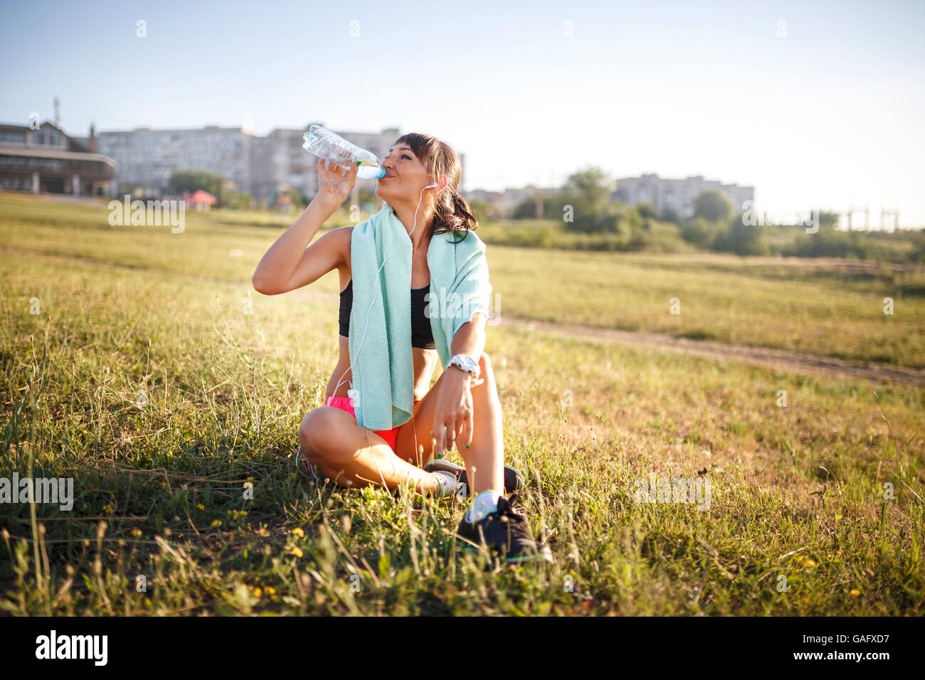 sport girl drinking water after sport. girl sitting on the grass ...