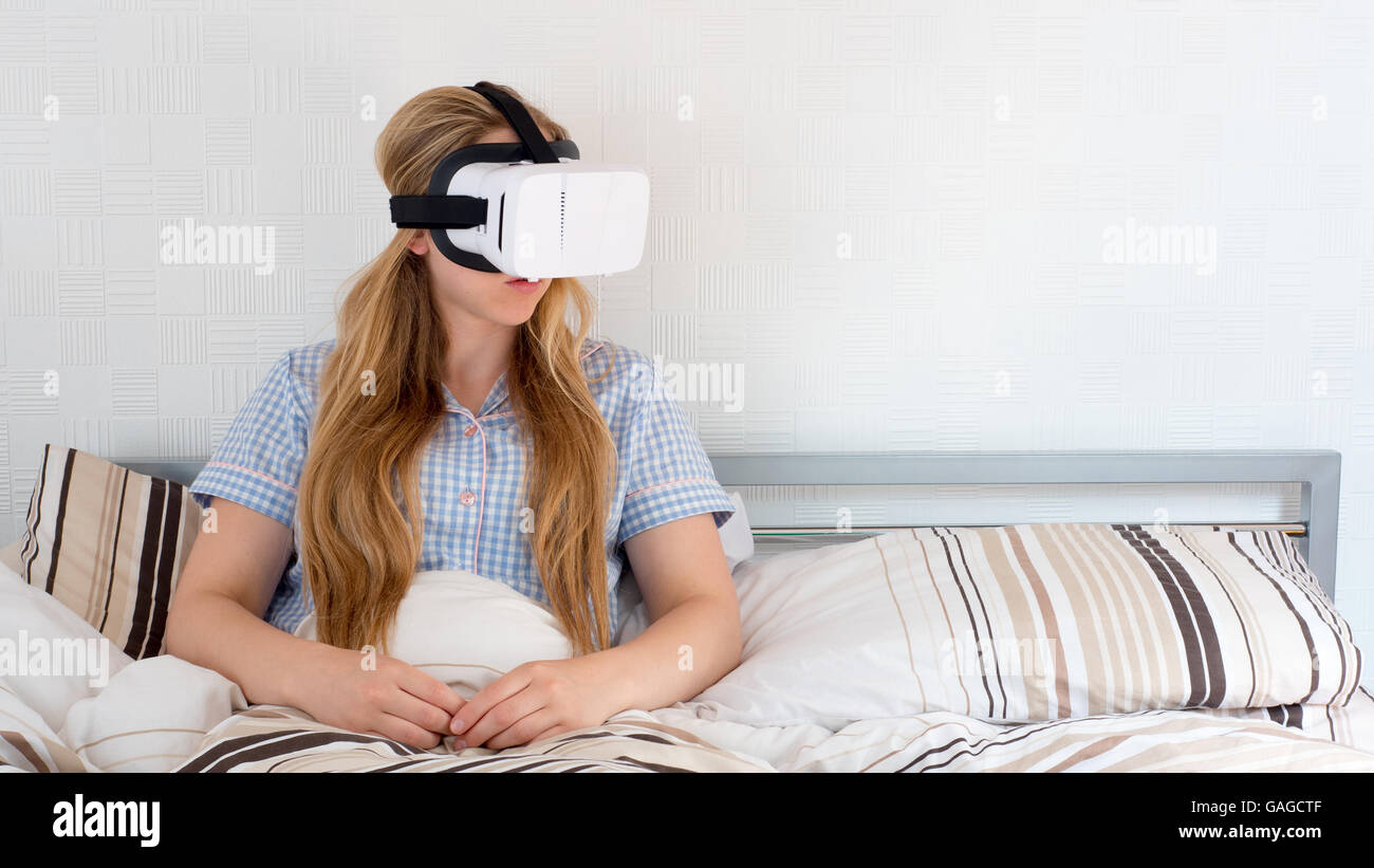 Beautiful woman using VR headset in bed Stock Photo - Alamy